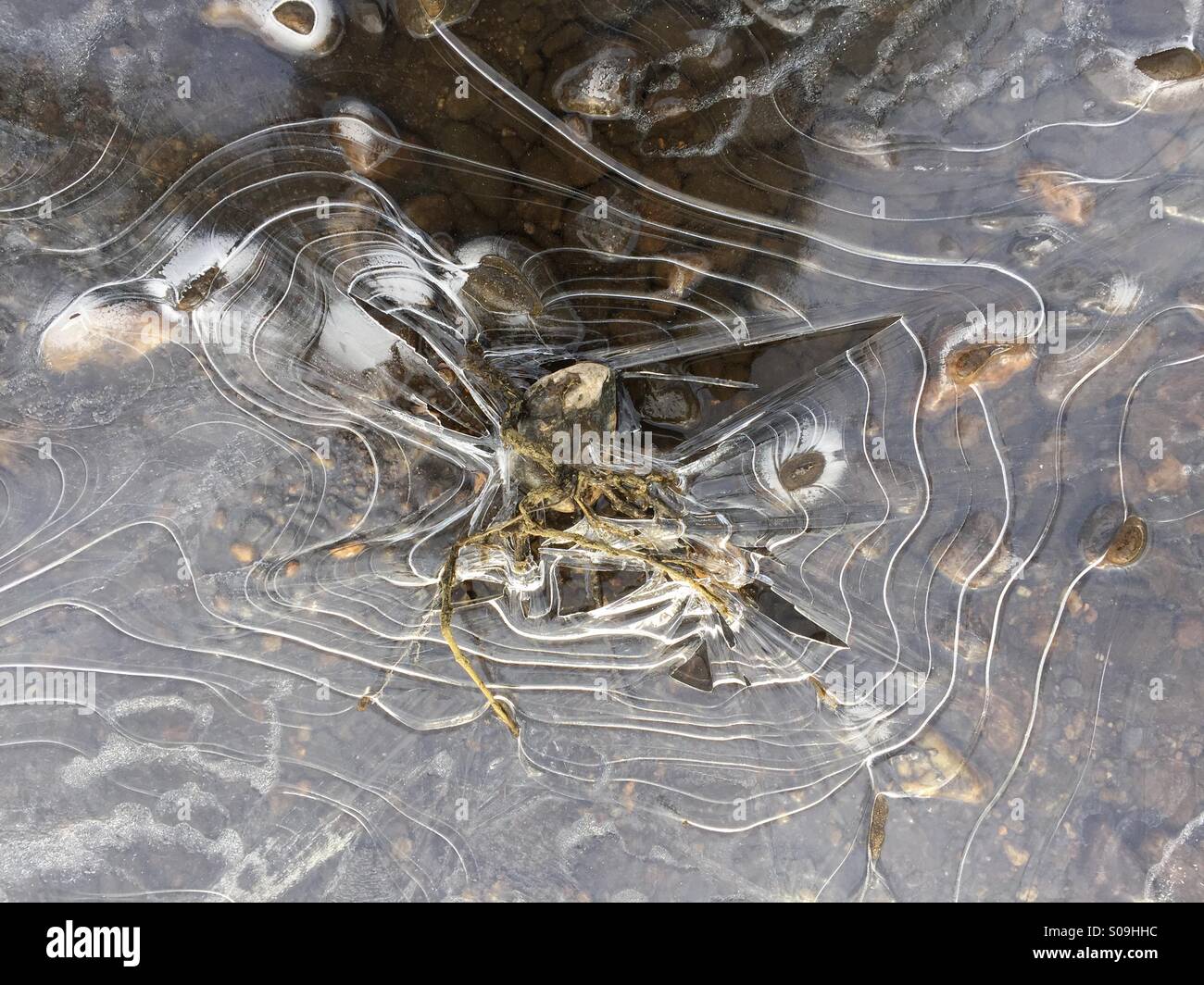 Ice pattern in stream with stones Stock Photo - Alamy
