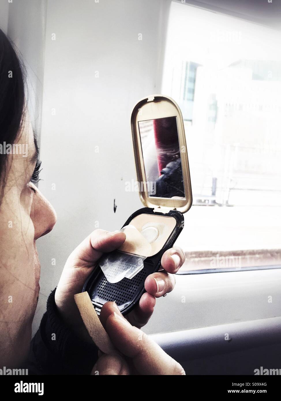 Woman applying makeup on commuter train Stock Photo - Alamy
