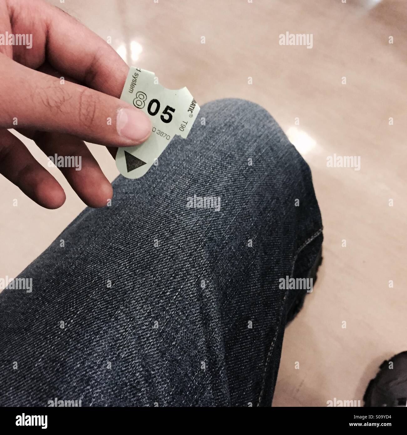 A person in a waiting room with a number in his hand Stock Photo - Alamy