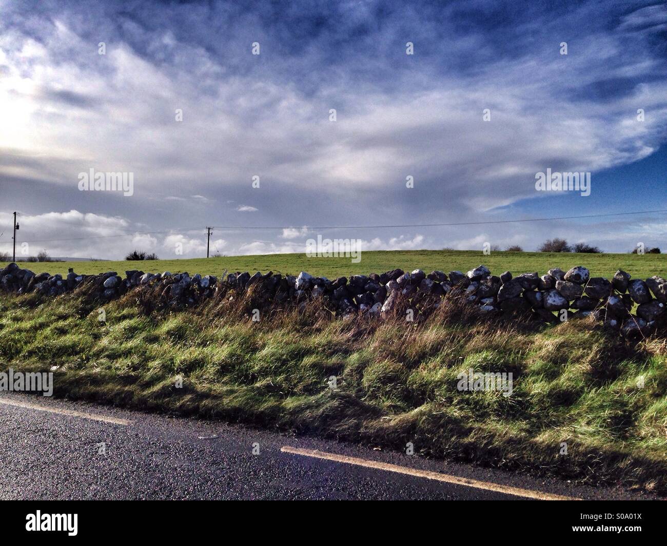 Irish landscape, green fields, stone fence, next to a country side road ...