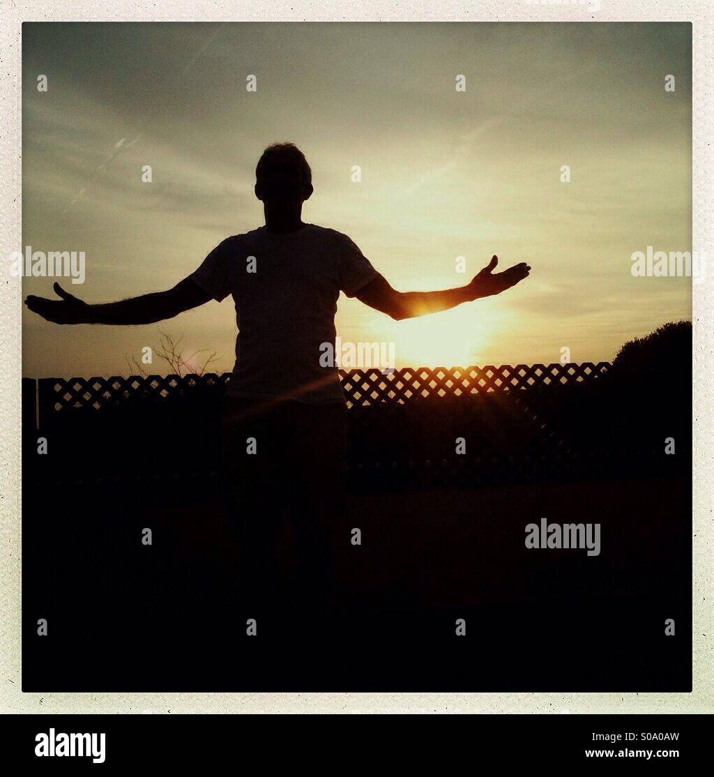 Silhouetted figure, arms out wide, sunset Stock Photo - Alamy