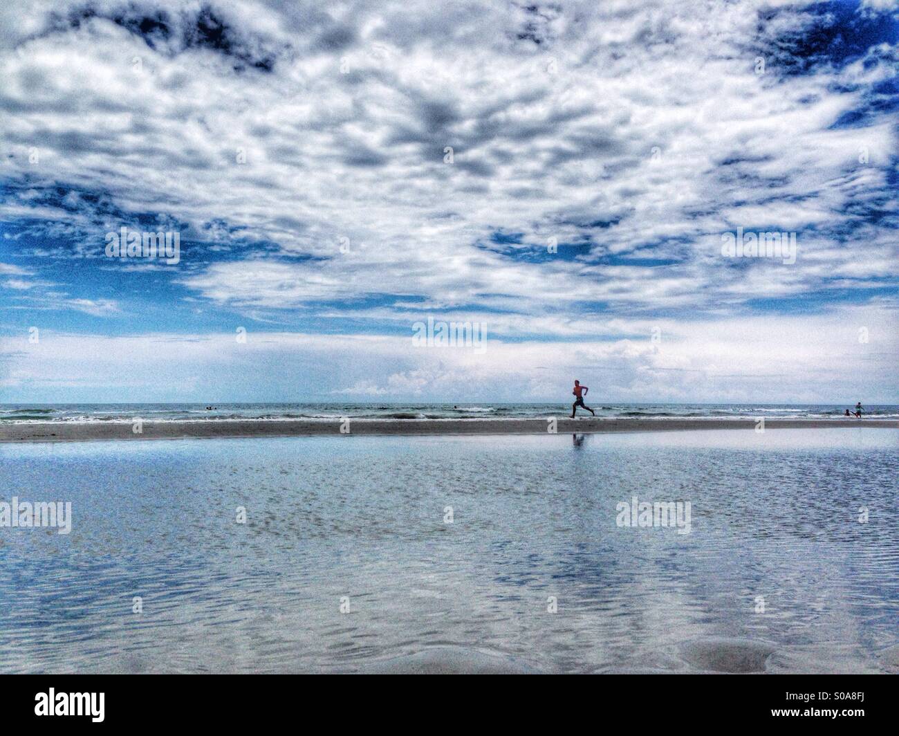 Running on the beach with clouds reflecting in the water Stock Photo ...