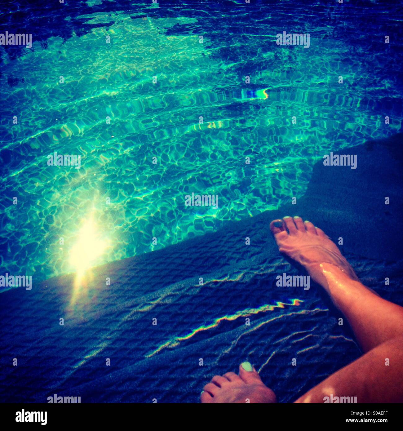 Woman sitting on pool's edge, feet in the water Stock Photo - Alamy