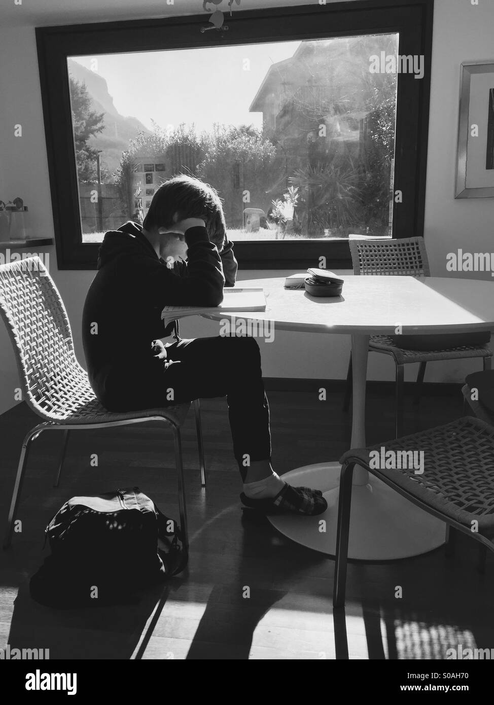 Kid doing homework sitting in front of a window Stock Photo - Alamy