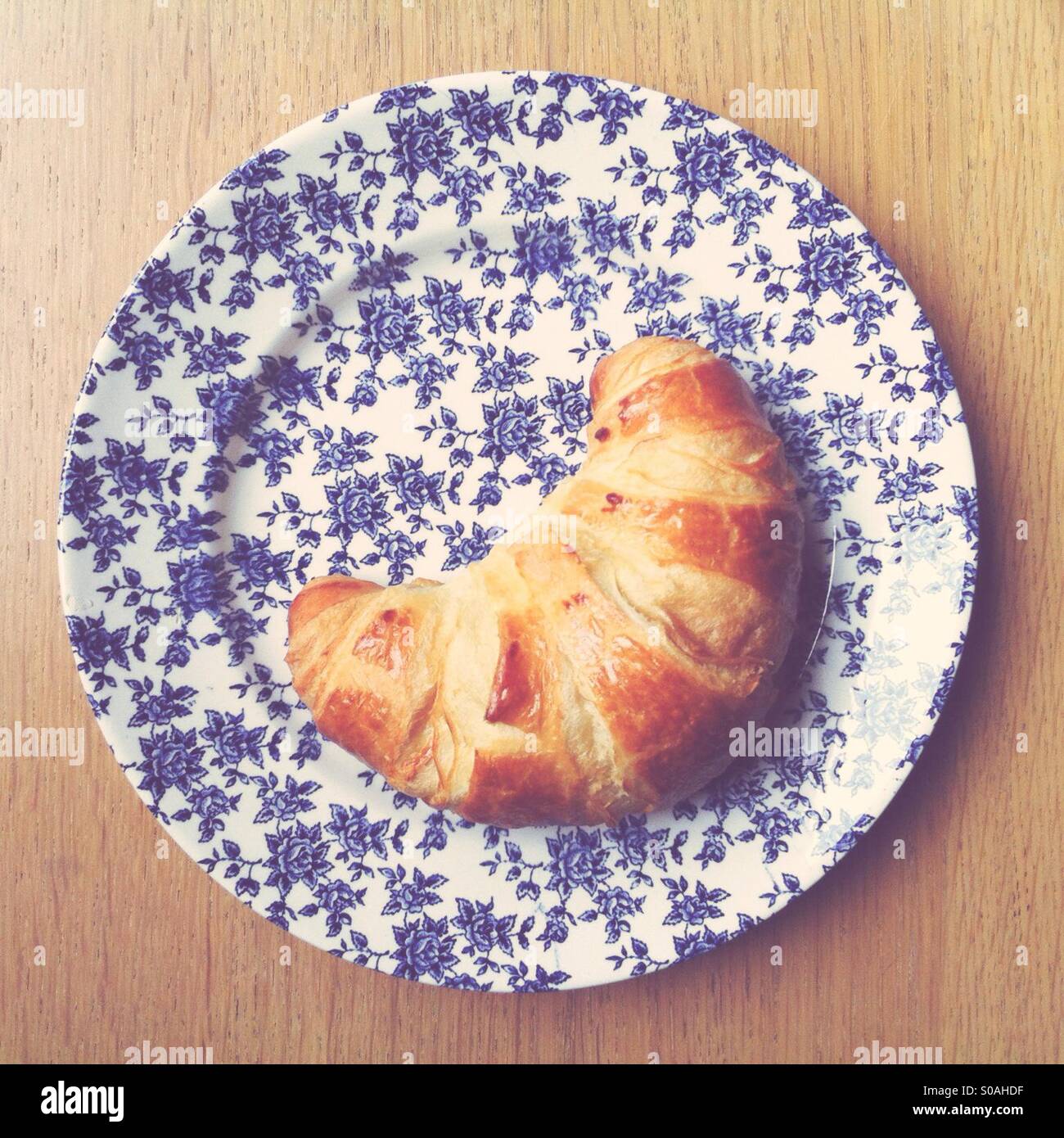 A croissant on a vintage blue floral plate Stock Photo - Alamy