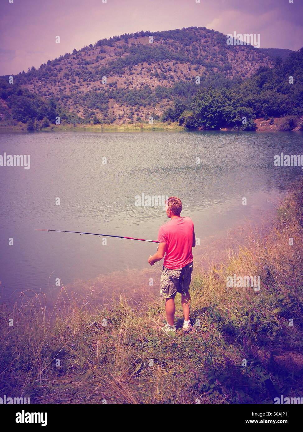 Young man fishing in lake, France Stock Photo - Alamy