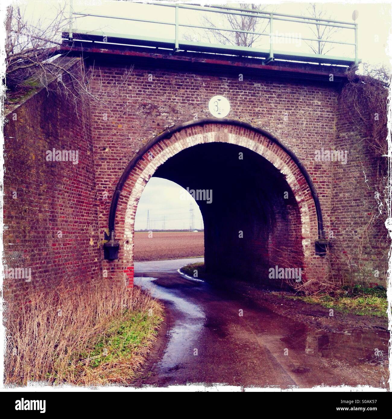 Underbridge road with field in background Stock Photo - Alamy