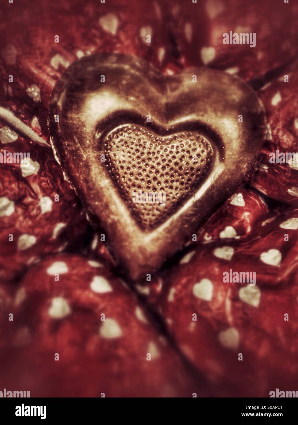 Red foil wrapped chocolate hearts with one opened Stock Photo - Alamy