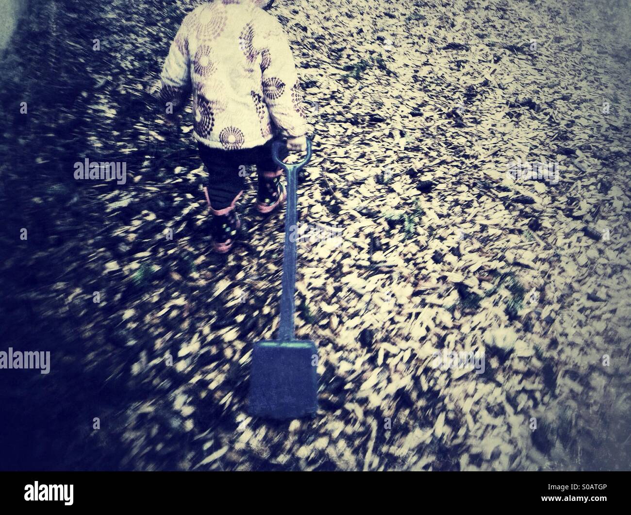 Toddler dragging a large shovel on a playground Stock Photo - Alamy