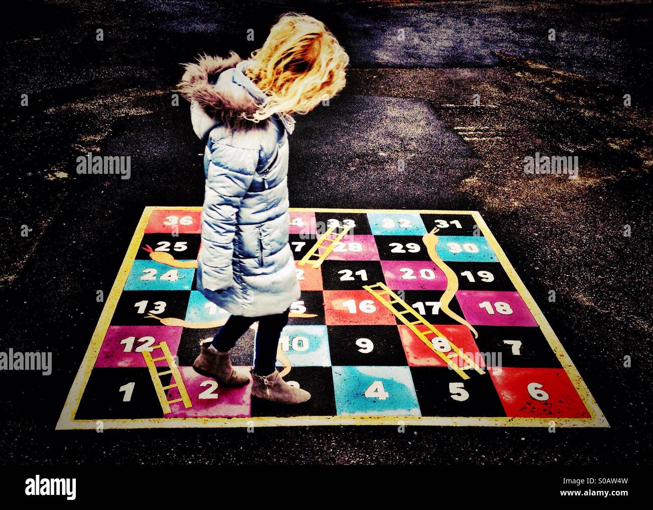 Young girl playing on giant snakes and ladders board Stock Photo - Alamy