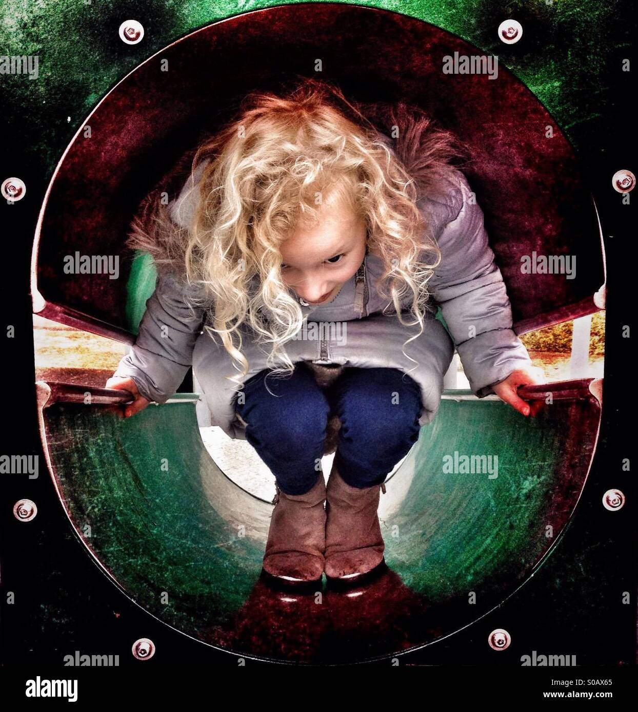 Girl climbing through tube in play apparatus Stock Photo - Alamy
