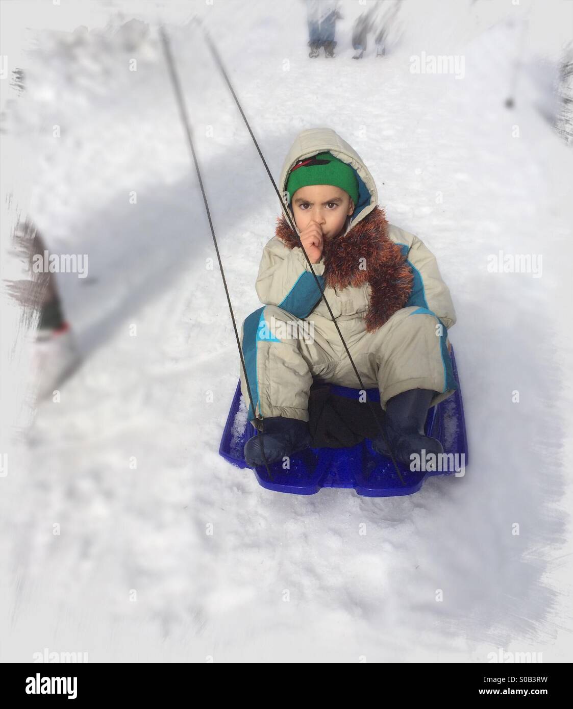 Boy sledding in snow Stock Photo - Alamy