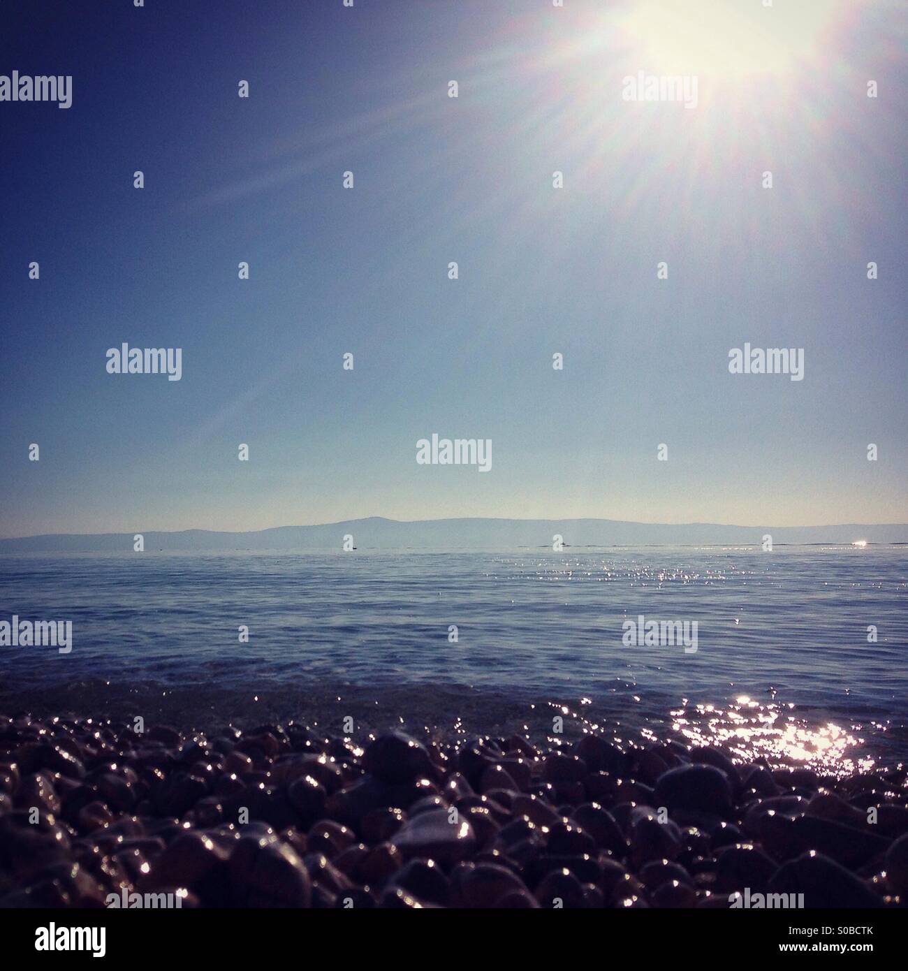 Sunny day on pebble beach Stock Photo - Alamy