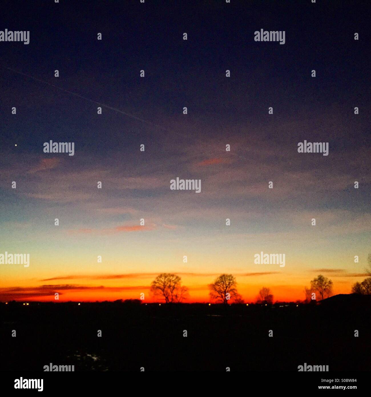 Sunset over Fields with Trees in Silhouette Stock Photo - Alamy