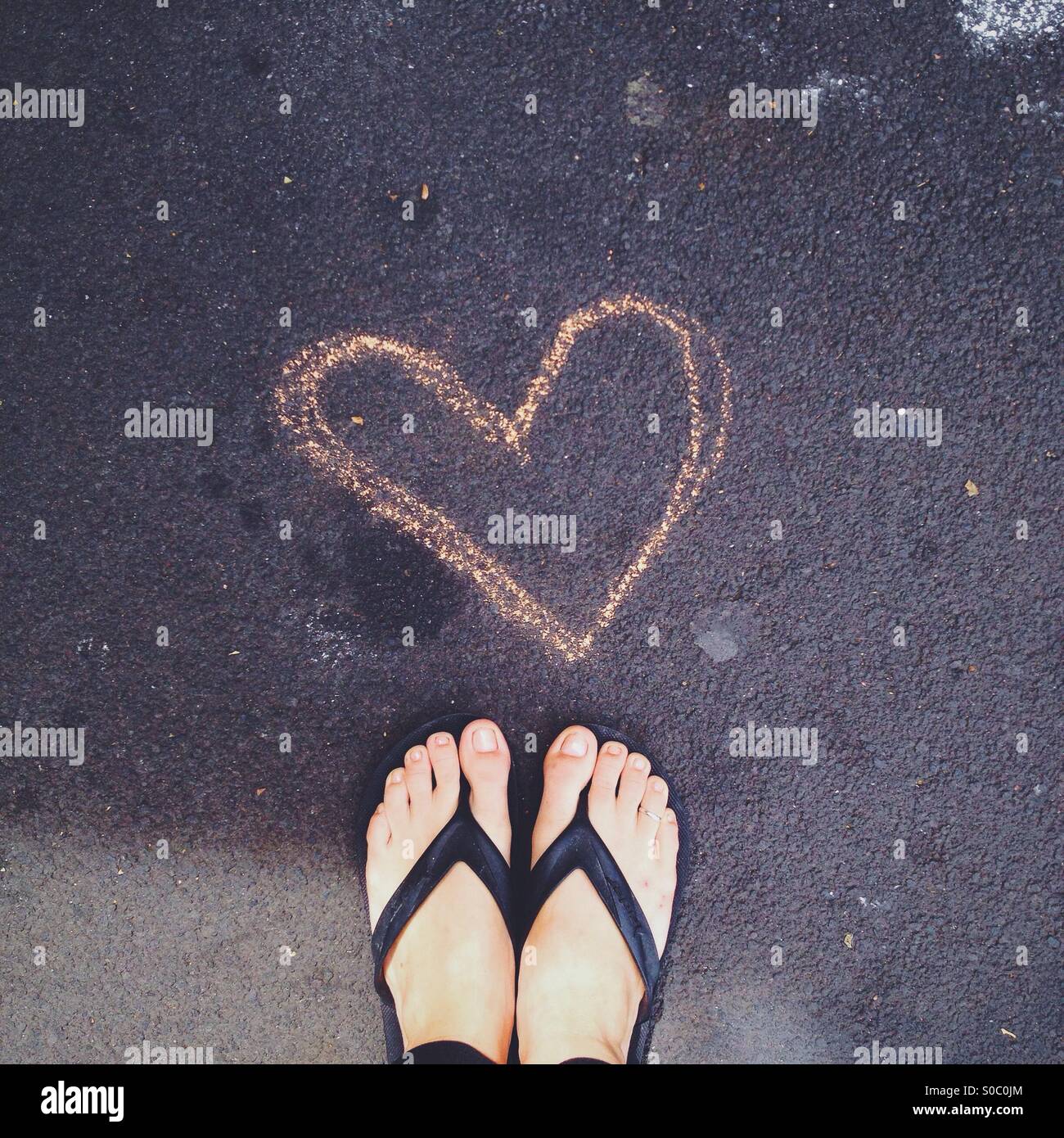 Pink chalk heart drawn on pavement with feet in sandals Stock Photo - Alamy
