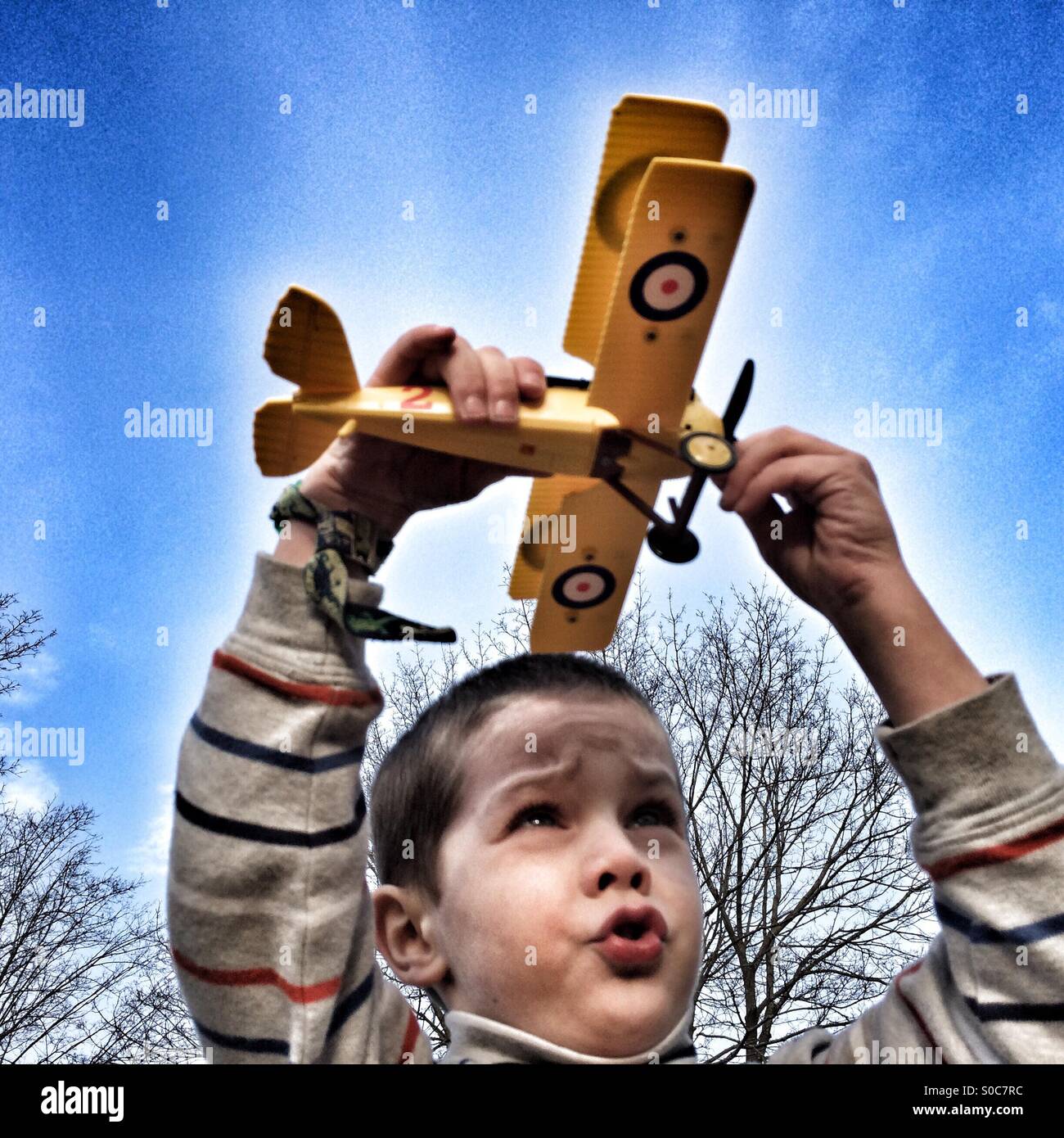 Child playing with airplane toy, boy imagines discovery adventure, blue ...