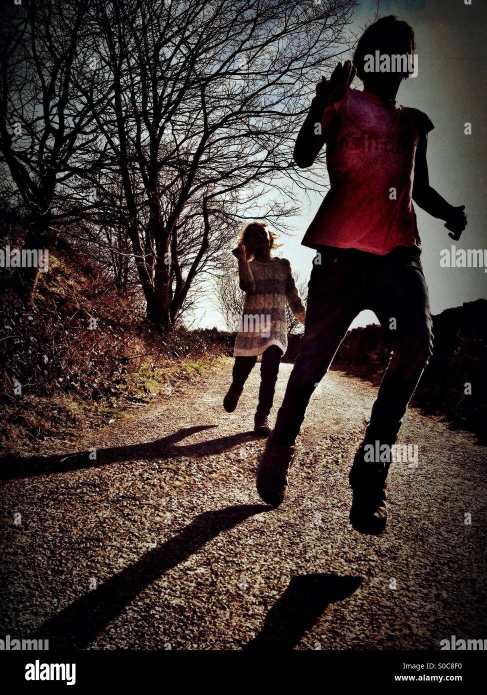 Two Young girls playing chase backlit by sun Stock Photo - Alamy