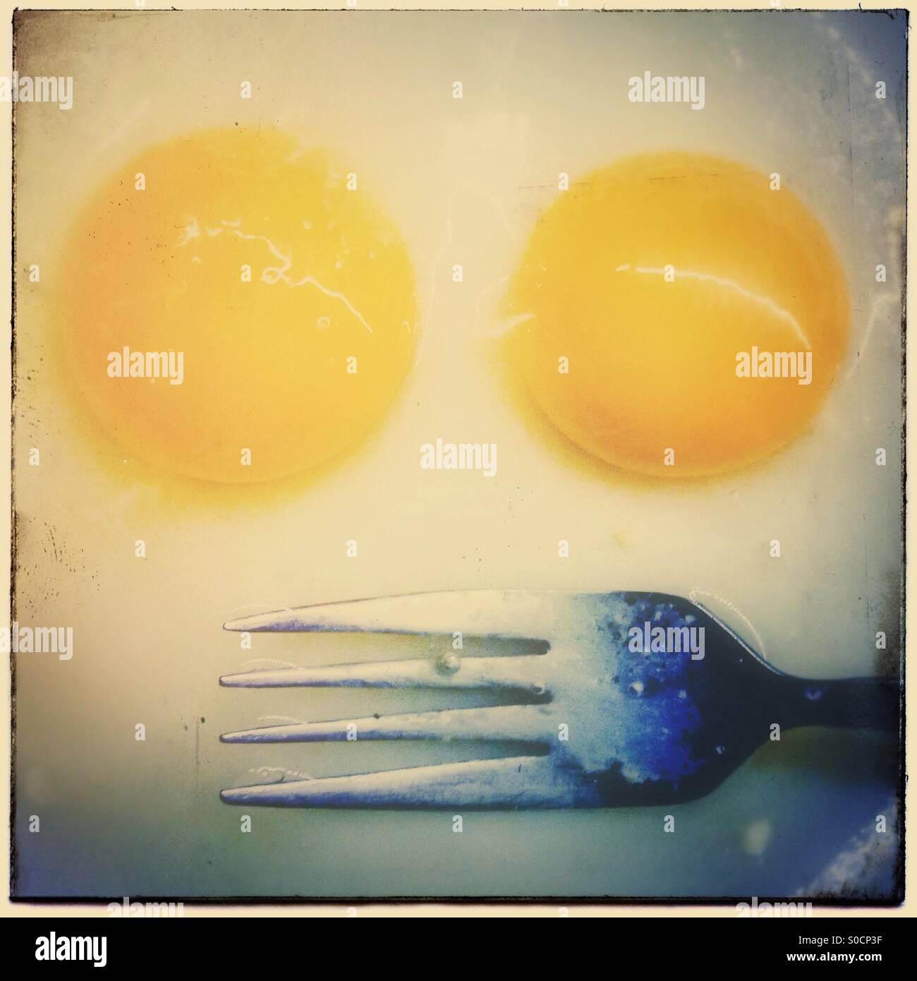 Two broken egg yolks and a fork. Faces in objects Stock Photo - Alamy