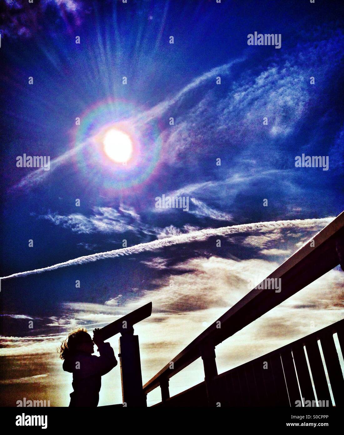 Girl looking through telescope against dramatic sky Stock Photo - Alamy