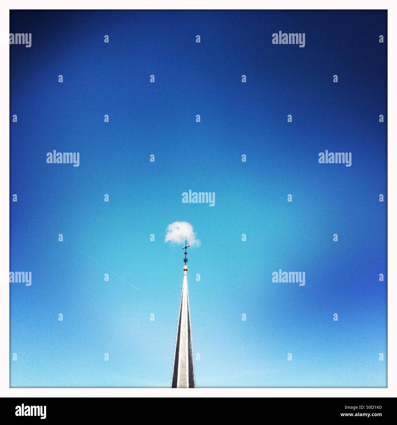 One small cloud in a blue sky touching the tip of a church Stock Photo ...