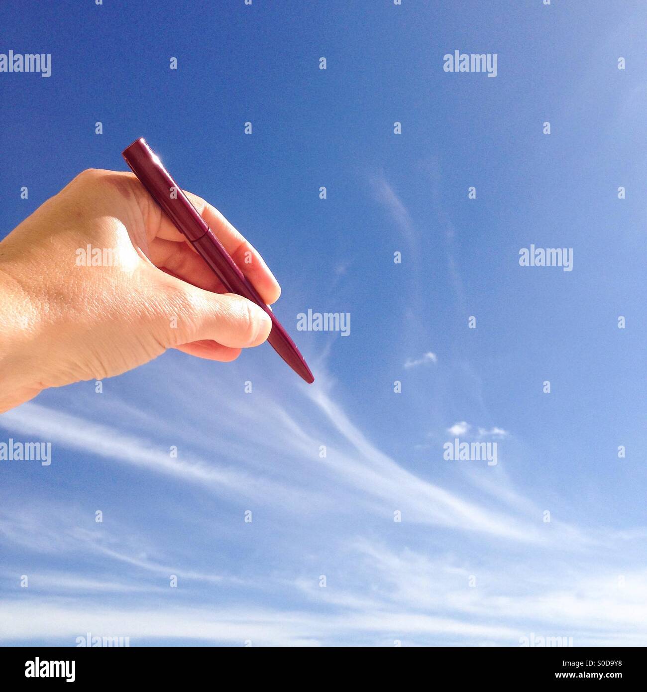 A hand and pen drawing clouds onto a blue sky Stock Photo - Alamy