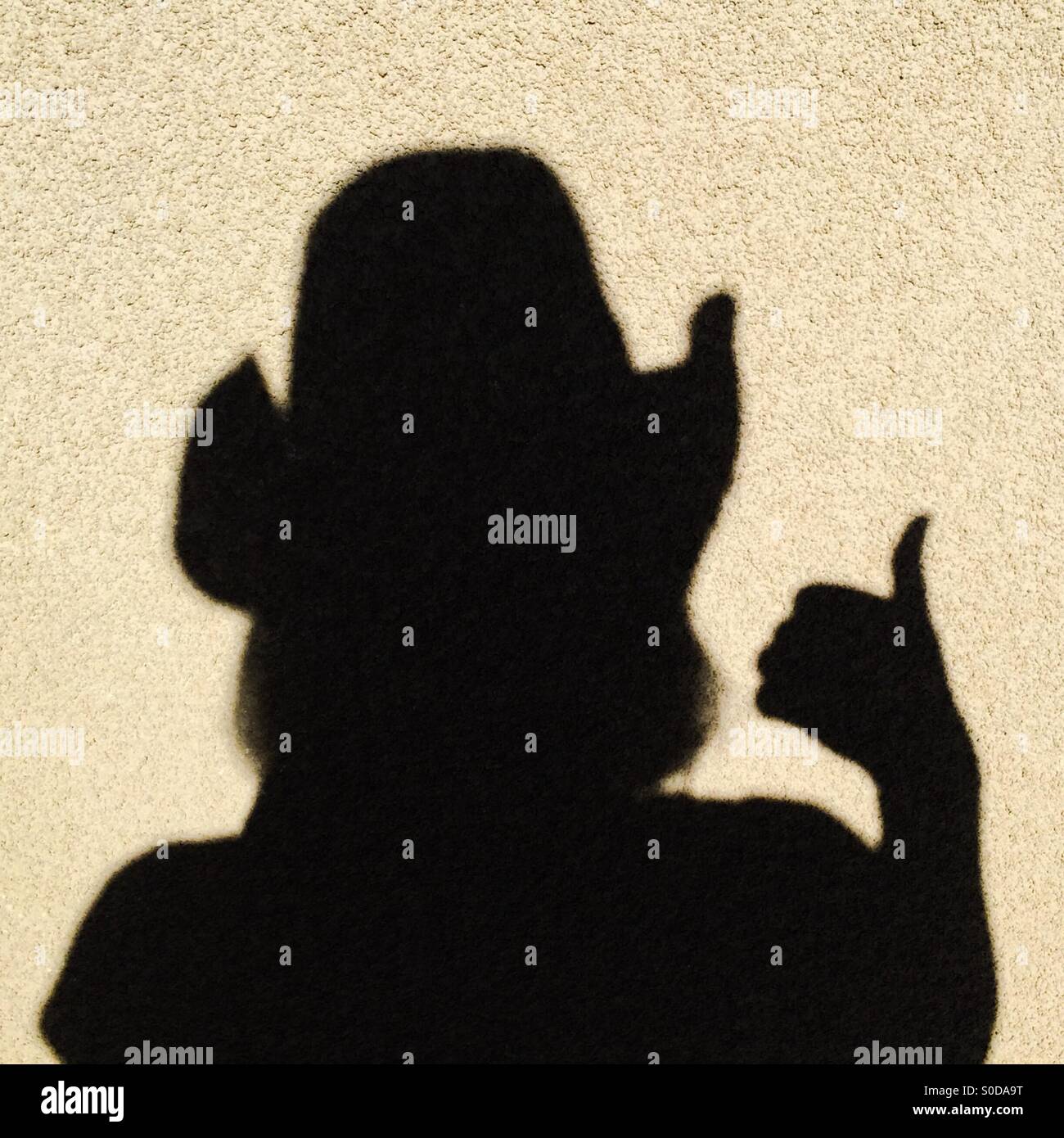 Shadow of a female wearing a cowboy hat with a thumbs up hand signal ...