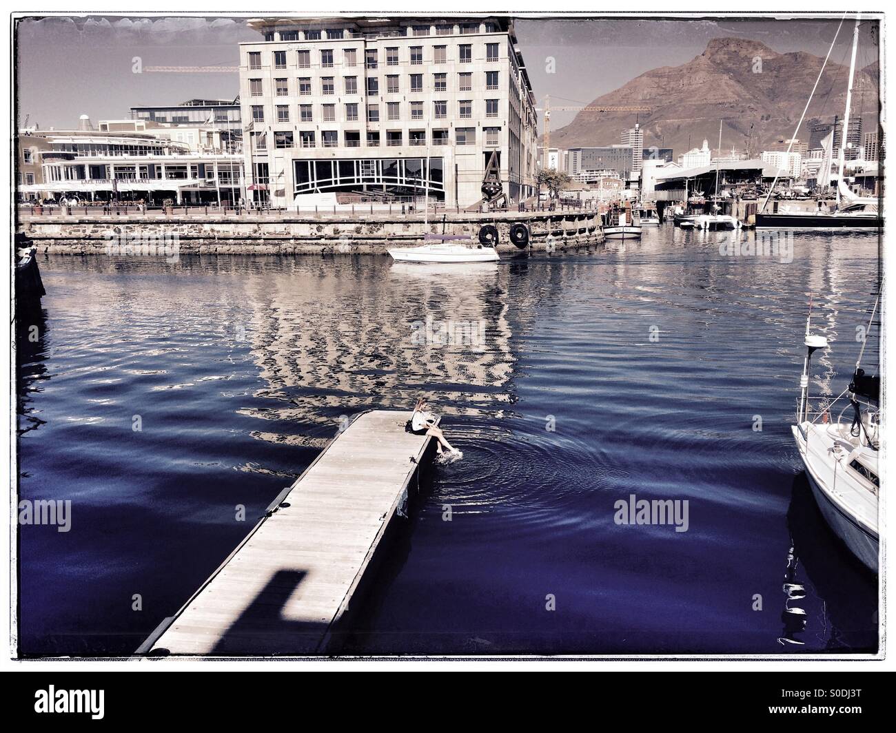 Woman sitting on a jetty in the V&A Waterfront in Cape Town, South ...
