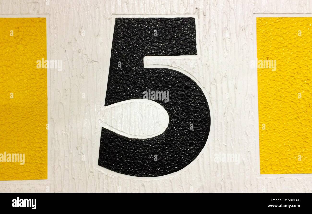 Number 5 / five painted on a textured concrete wall in black with ...