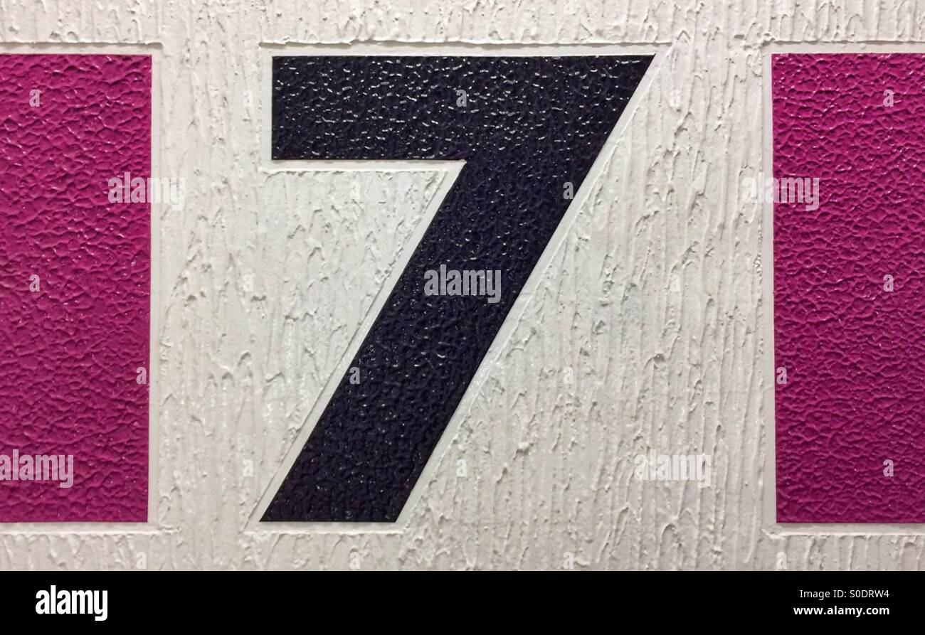 Number 7 / seven painted on a textured concrete wall with purple ...