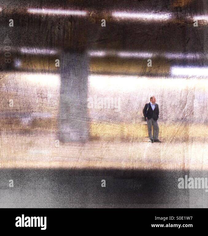 Man leaning against a railing and waiting for the metro in a subway ...