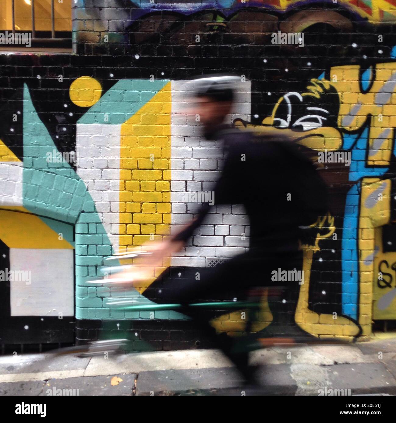 Blurred man on bike with street art in the background Stock Photo - Alamy