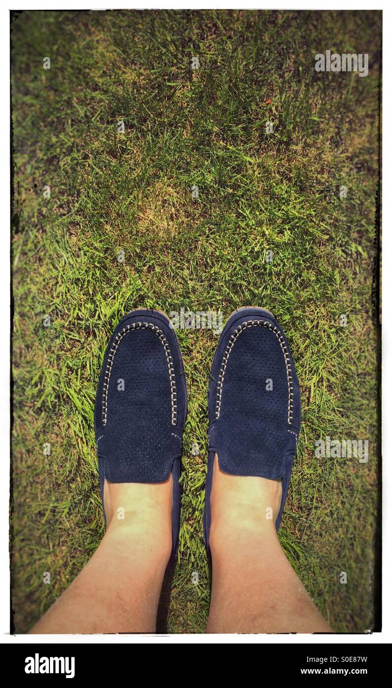 Person wearing blue suede shoes standing on a lawn taken from a first ...