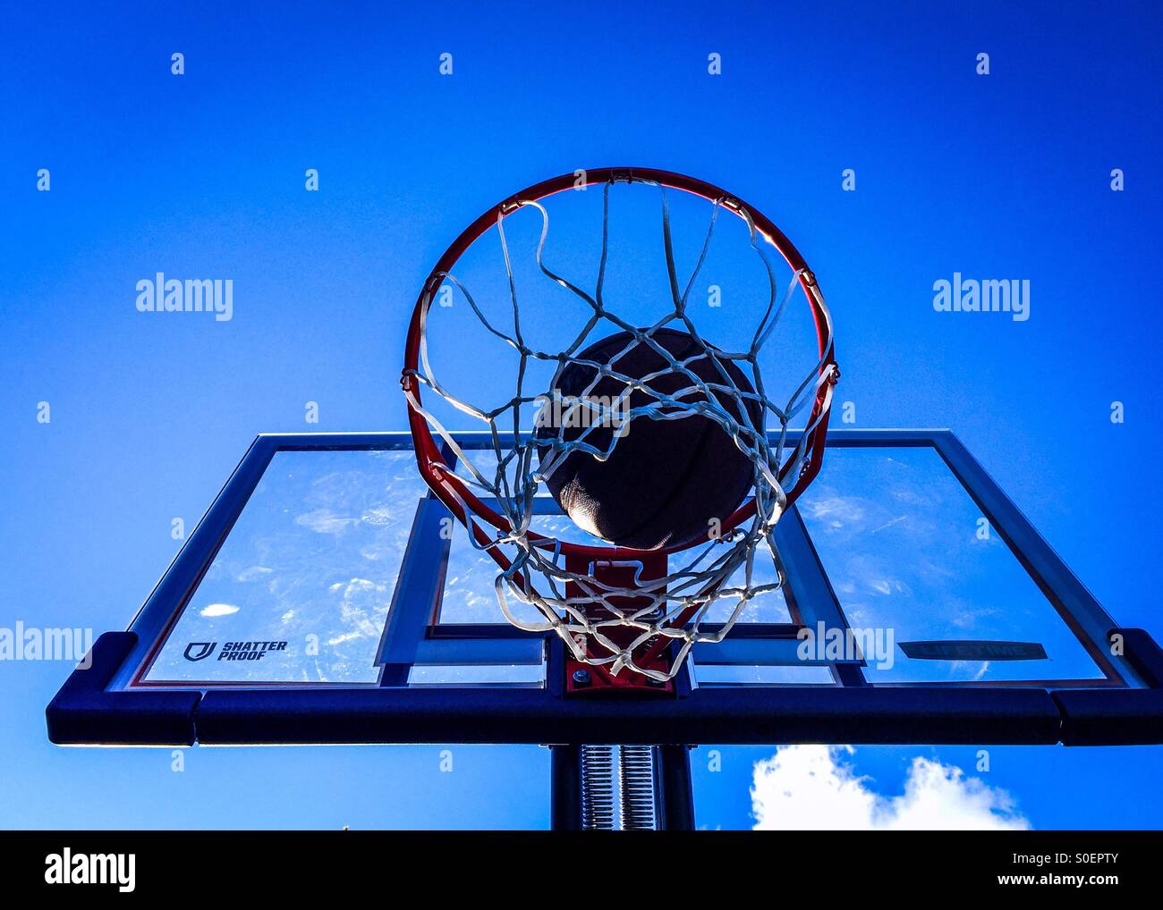 Looking up at basketball going through the basket. Blue sky in the ...