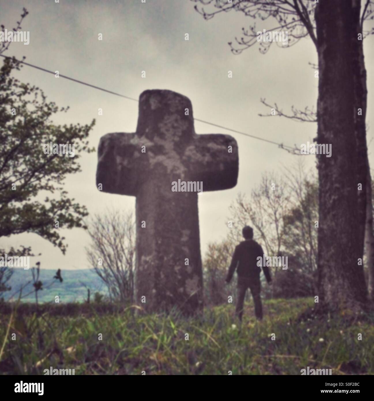 Perspective shot of man standing next to a big cross Stock Photo - Alamy