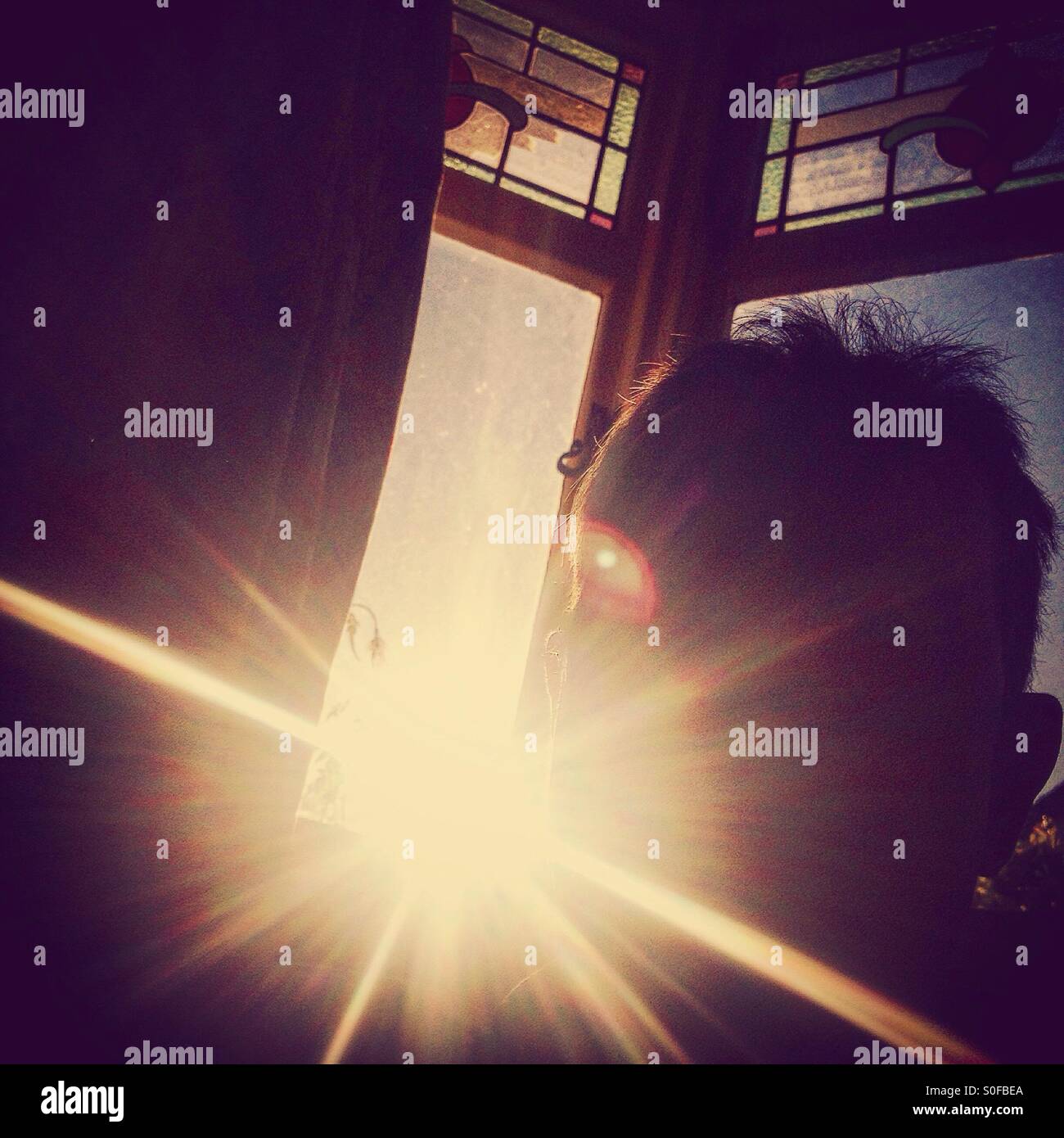 Man sitting in front of stained glass window with sunshine streaming ...