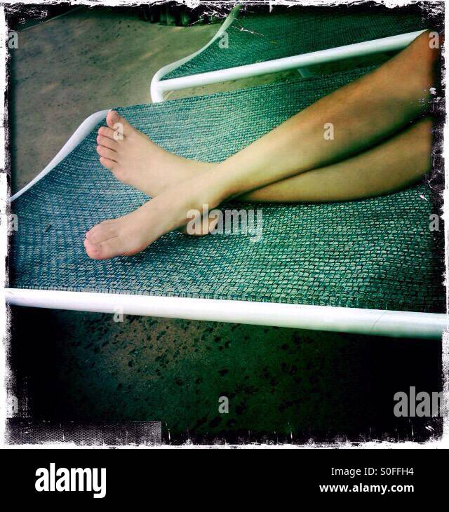 Legs relaxing on lounge chair Stock Photo - Alamy