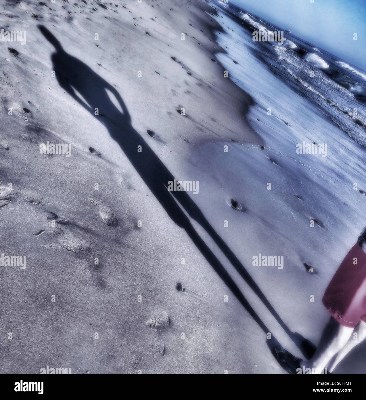 A Man And His Tall Shadow Reflected On The Sand At The Beach Stock ...