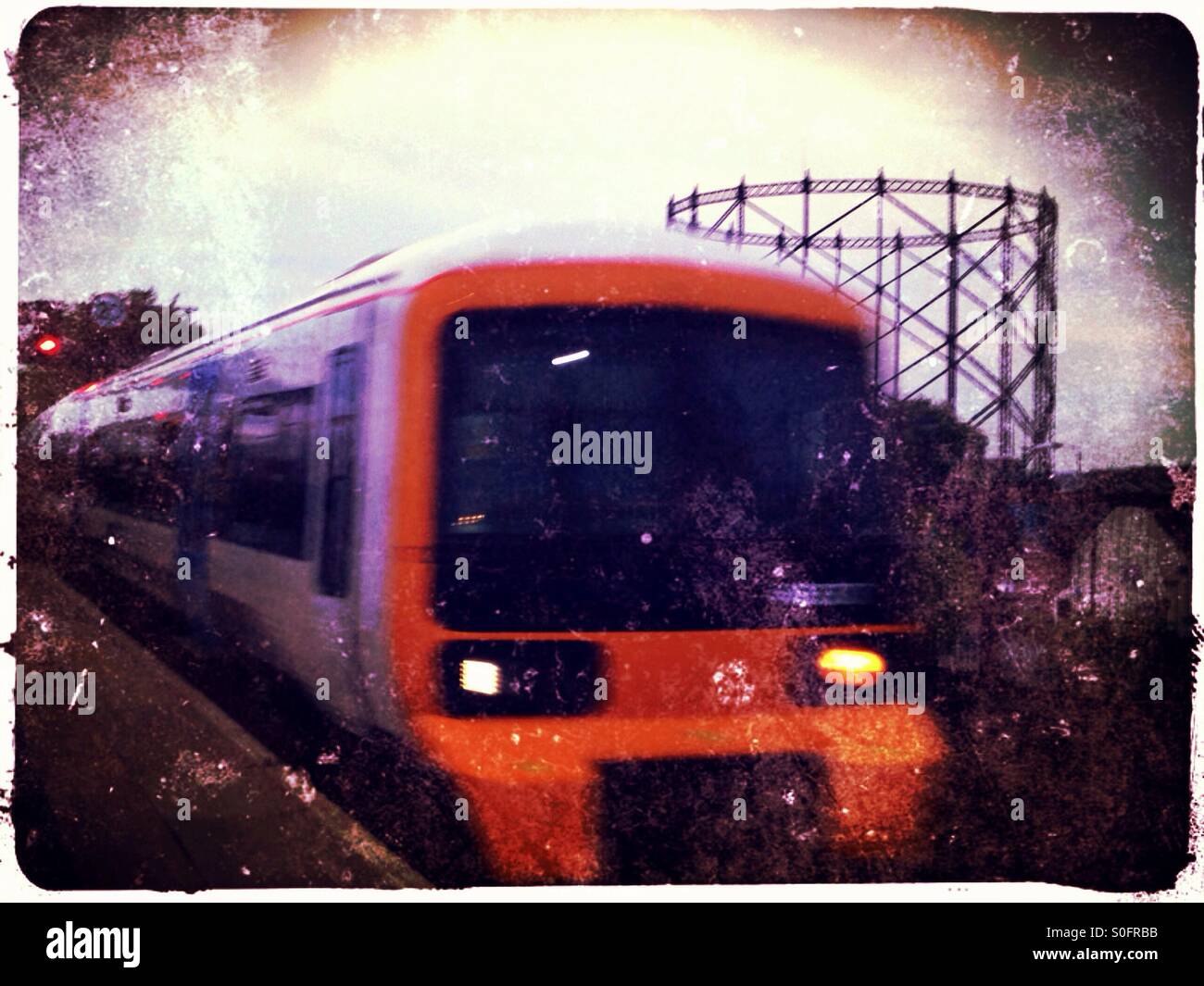 Train arriving at platform showing gasometer in distance, Dartford ...