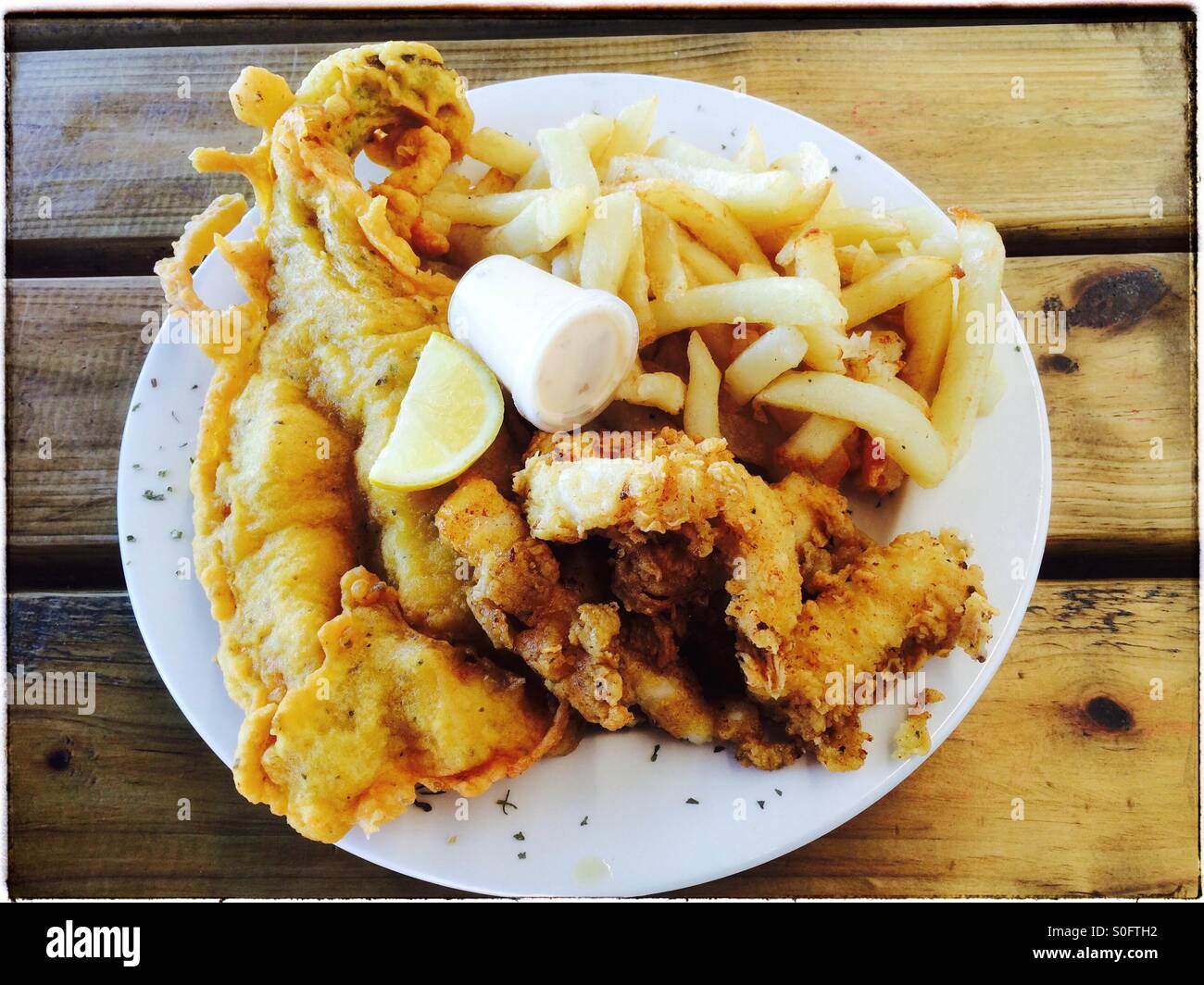 Fried fish, calamari and chips with tartar sauce at seafood restaurant ...