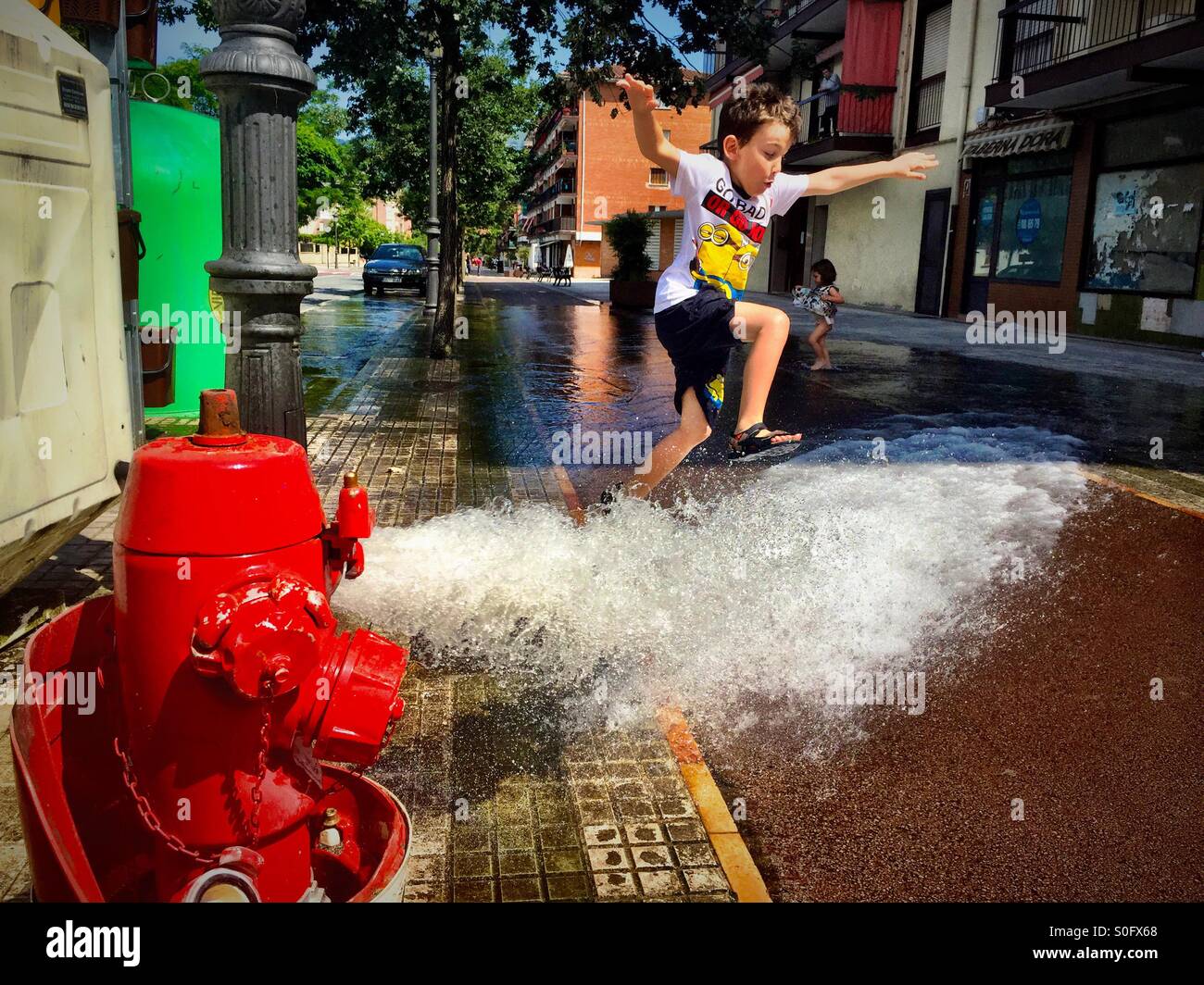 Summer fun- boy leaping over water hydrant stream Stock Photo - Alamy