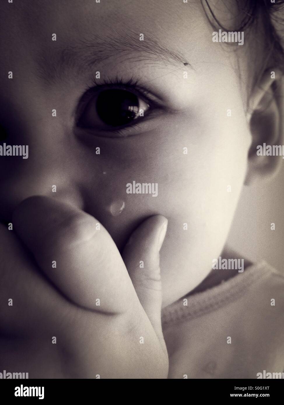 Baby girl crying with hand covering her mouth Stock Photo - Alamy