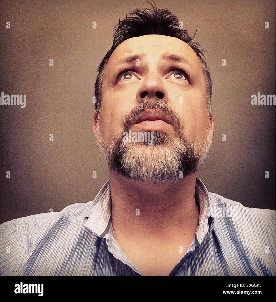 Pictures from below, man with beard looking out window Stock Photo - Alamy