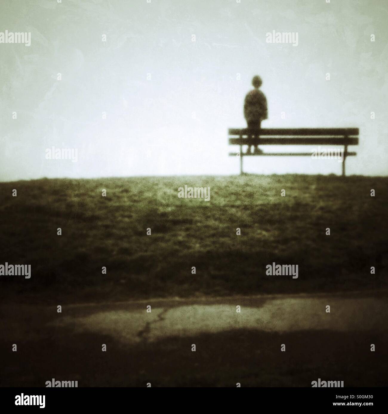Child waiting standing on a park bench Stock Photo - Alamy
