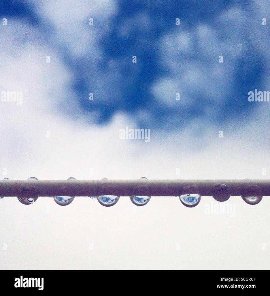 Water droplets on a washing line with blue sky and clouds behind Stock ...