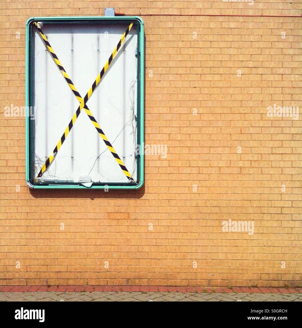 Broken sign on a wall, with an X made from hazard tape Stock Photo - Alamy