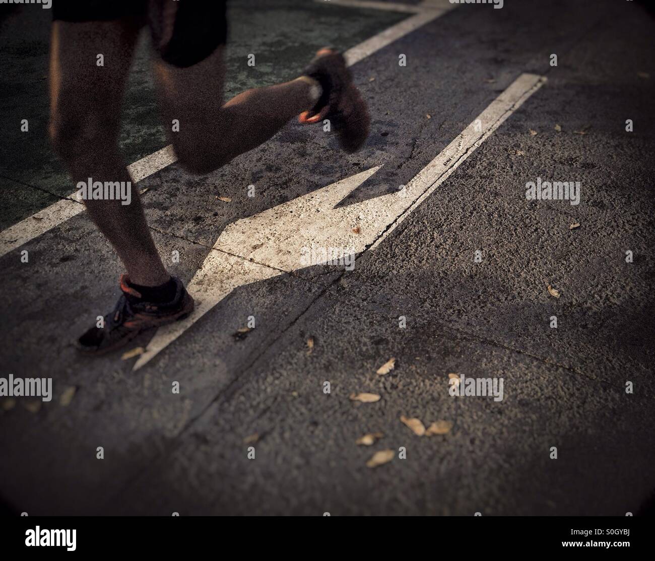 Runner and arrow on asphalt Stock Photo - Alamy