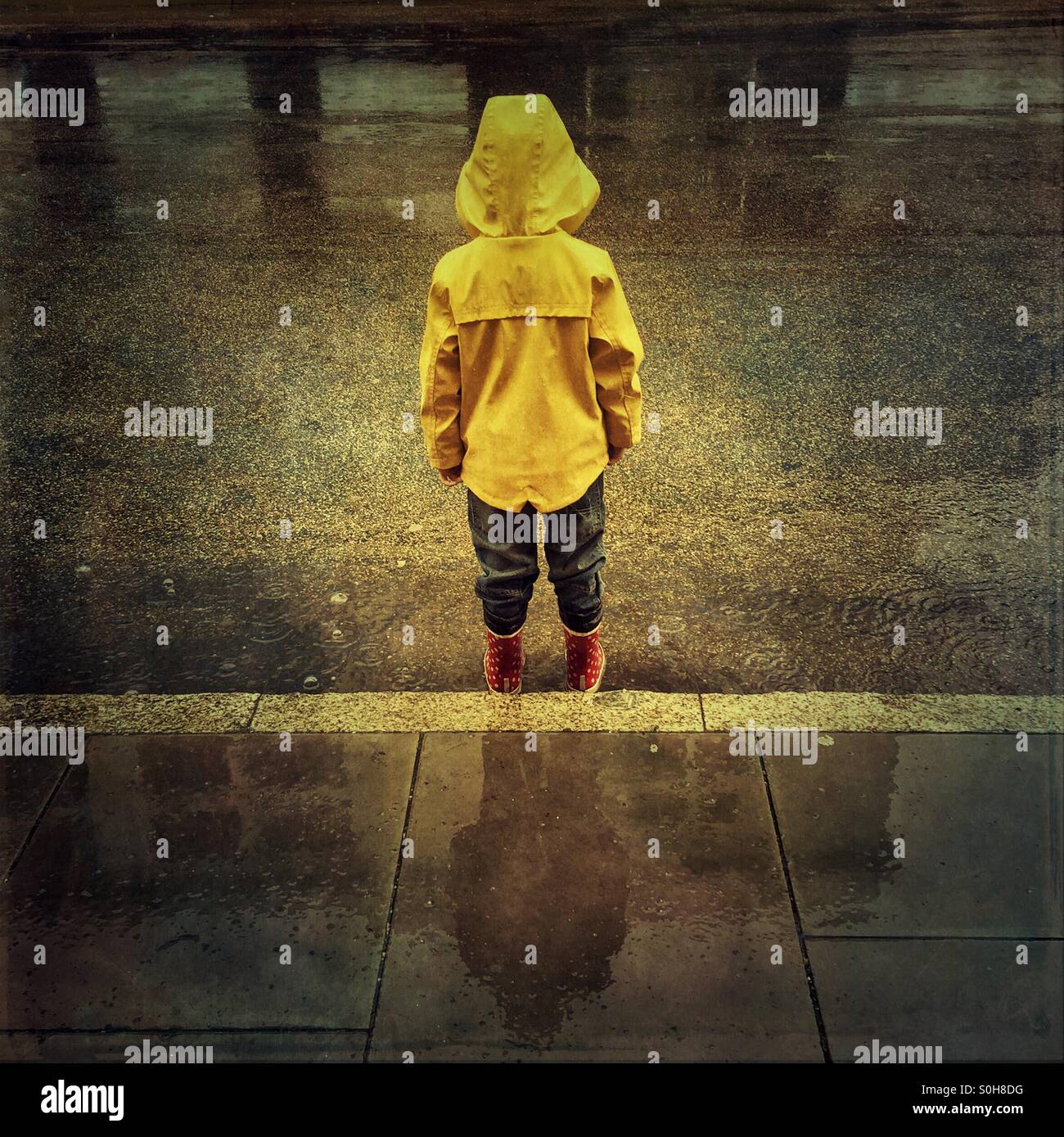 Child standing in a puddle in the rain Stock Photo - Alamy