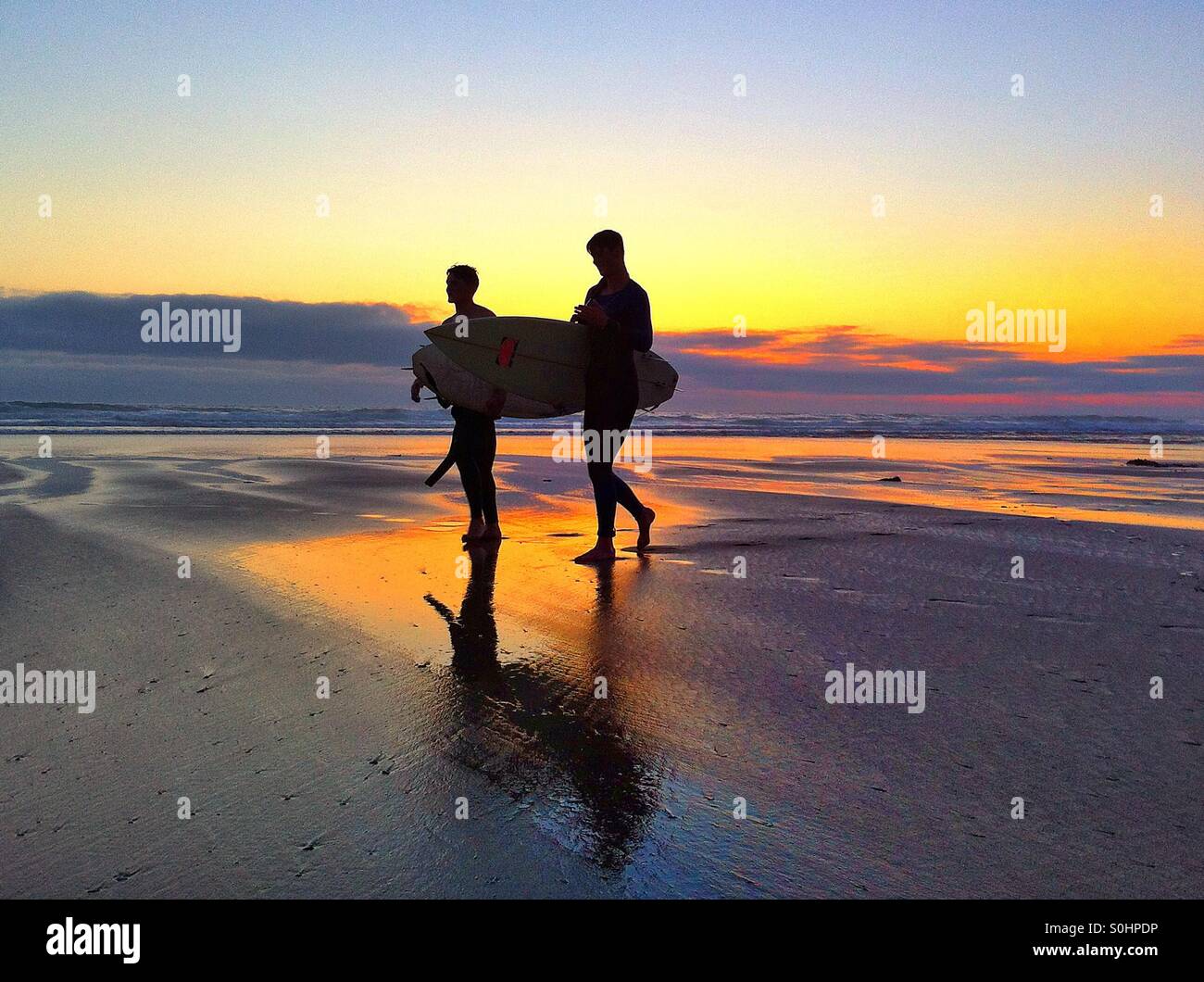 Surfers at sunset Stock Photo - Alamy