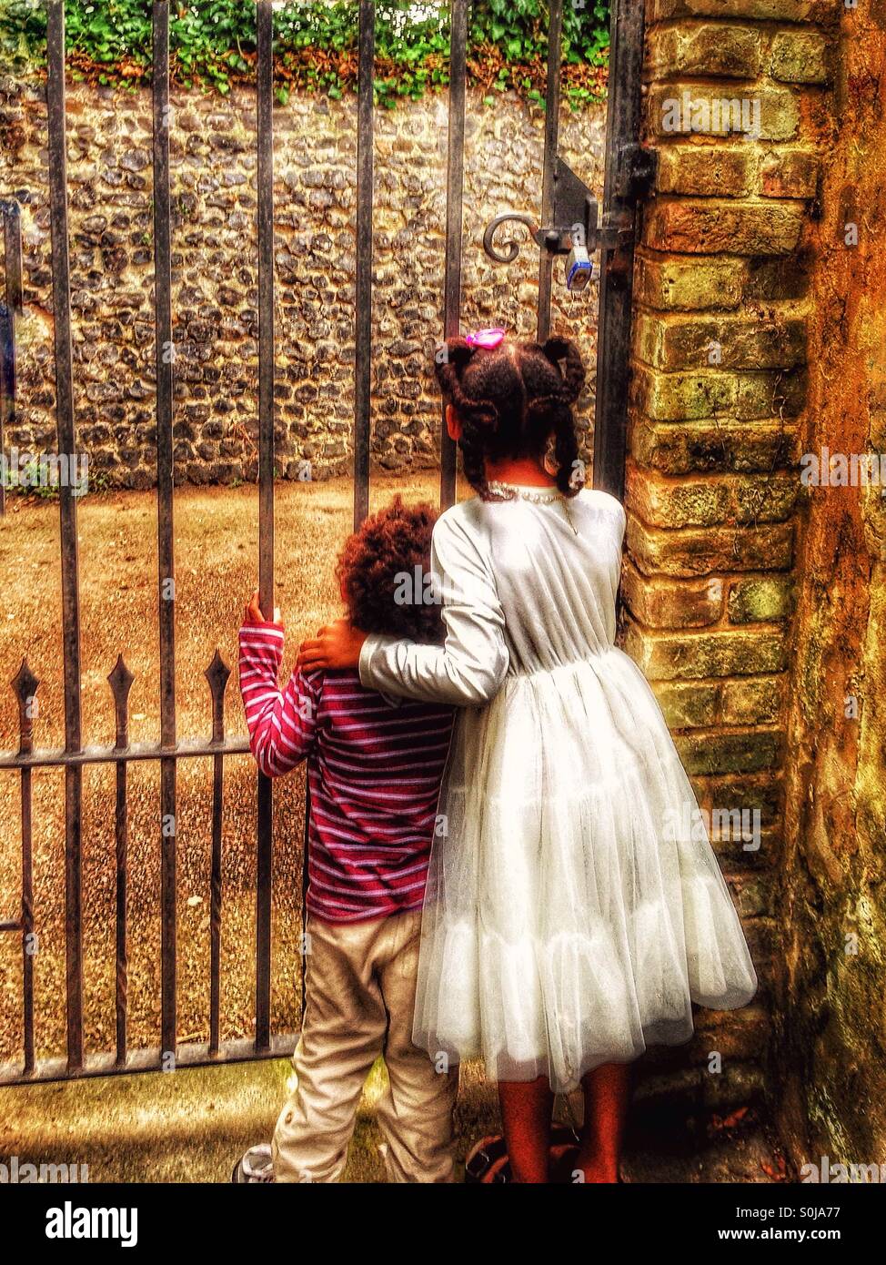 Children looking through the garden gate Stock Photo - Alamy