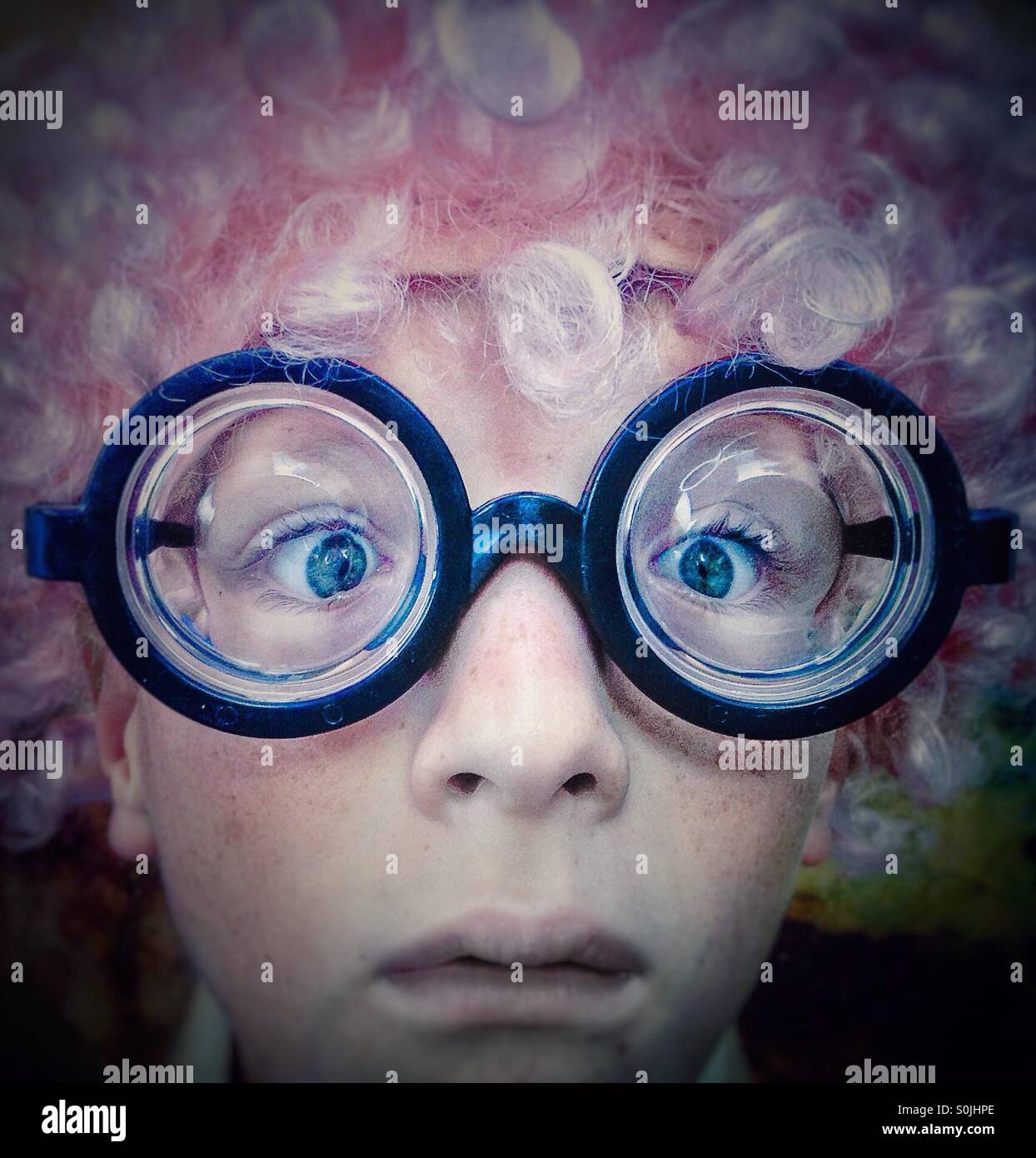 Portrait of a boy with pink wig and nerd eyes glasses looking at the camera Stock Photo - Alamy